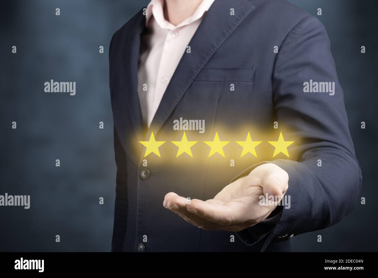 Businessman hand holding five stars on blue background. Businessman ...