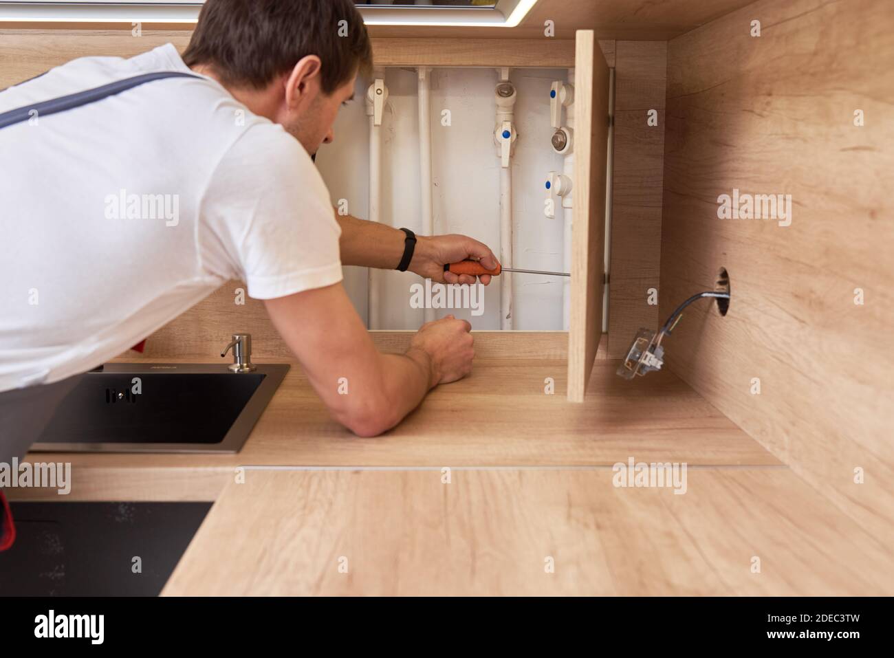 Man opens an assembly hatch and checks the water pipes Stock Photo - Alamy