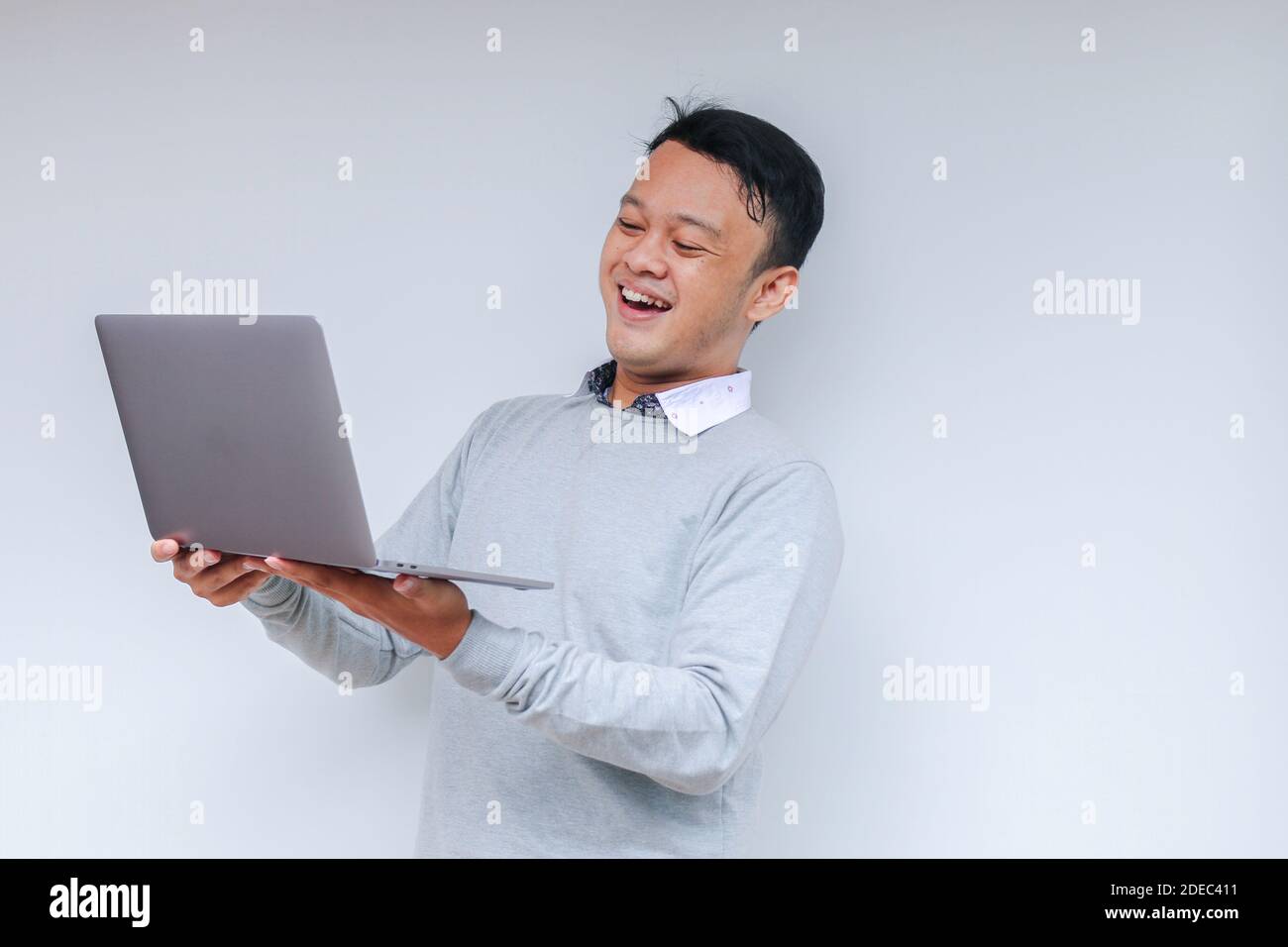 Young Asian man feeling happy and smile when standing and work laptop ...
