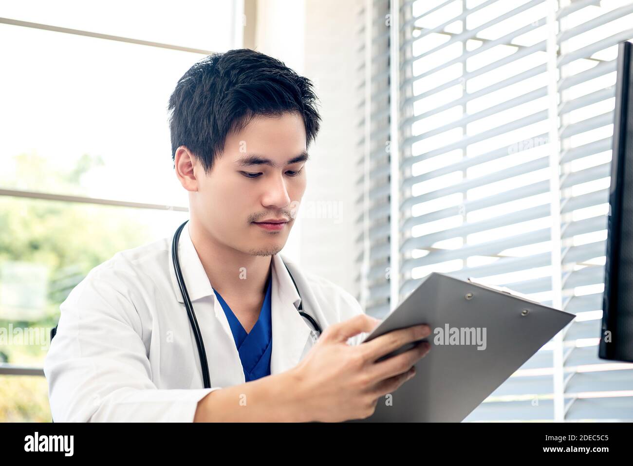Portrait of a young attractive male asian doctor going through his ...