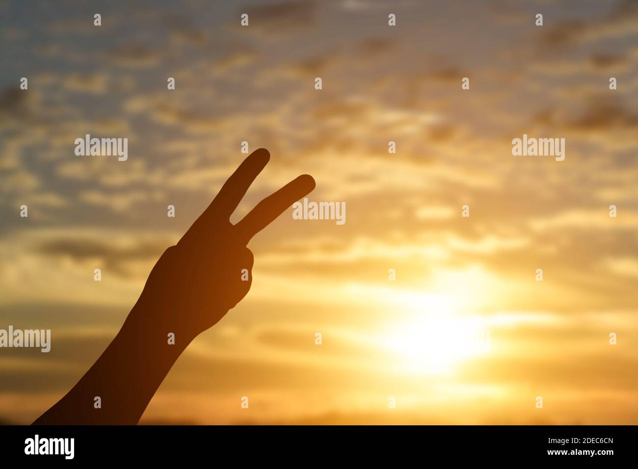 Silhouette of hand showing two fingers up over sunset background Stock ...