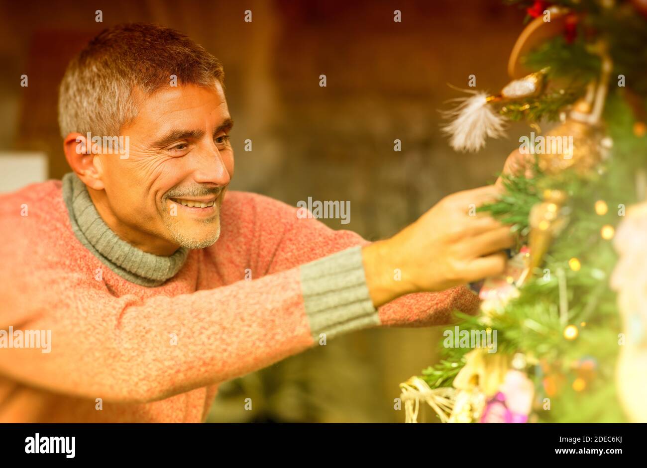 Happy Man decorating Christmas Tree at home Stock Photo - Alamy