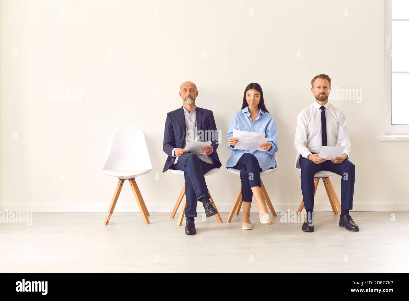 Group of business people sitting on chairs in the lobby and waiting for ...