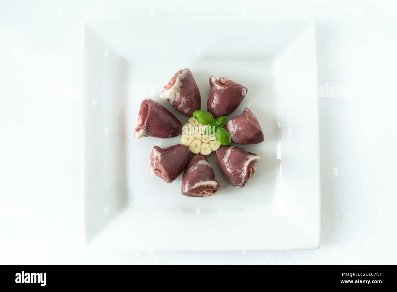 Raw turkey hearts on a white plate with garlic. View from above Stock ...