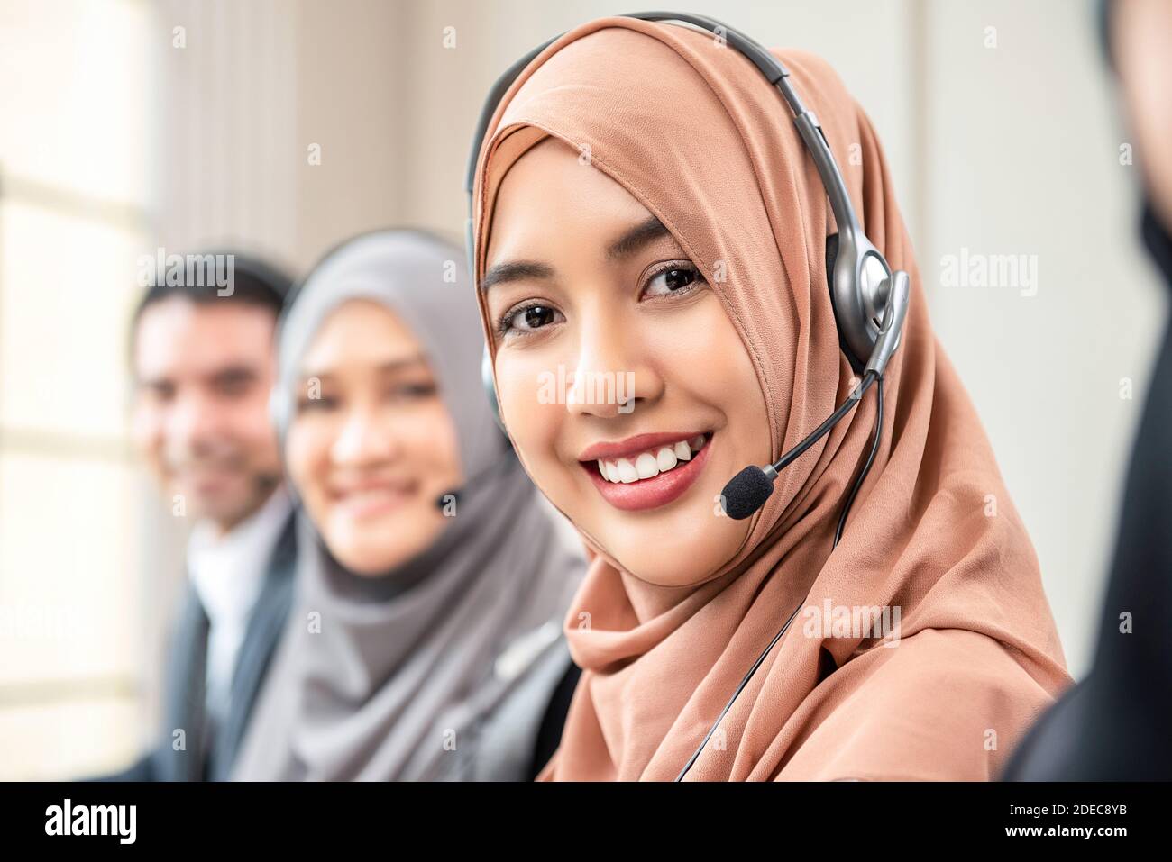 Friendly beautiful Asian muslim woman wearing microphone headset ...
