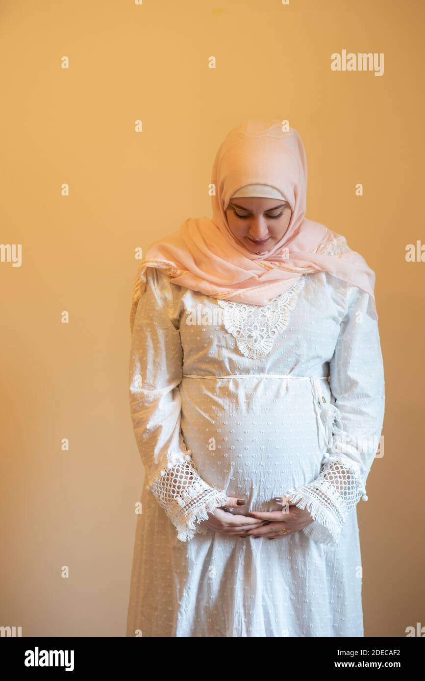Pregnant Muslim woman looking at her belly Stock Photo - Alamy