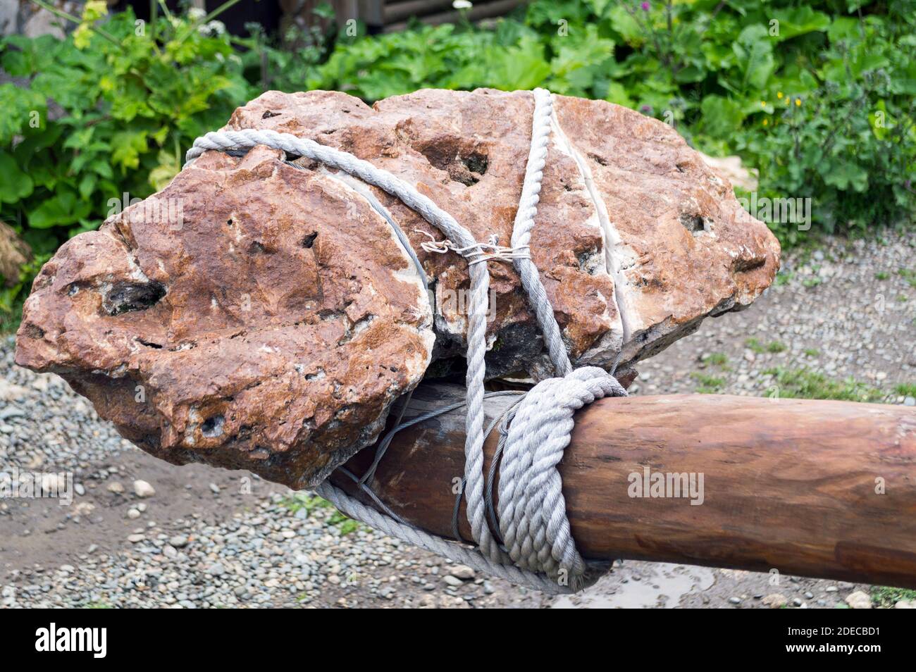 A large stone tied a thick rope to a wooden log Stock Photo - Alamy
