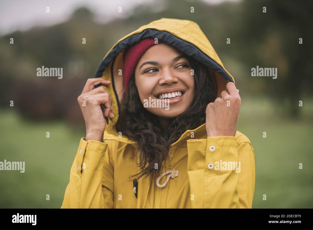 Pretty mulatta in yellow coat looking happy Stock Photo - Alamy