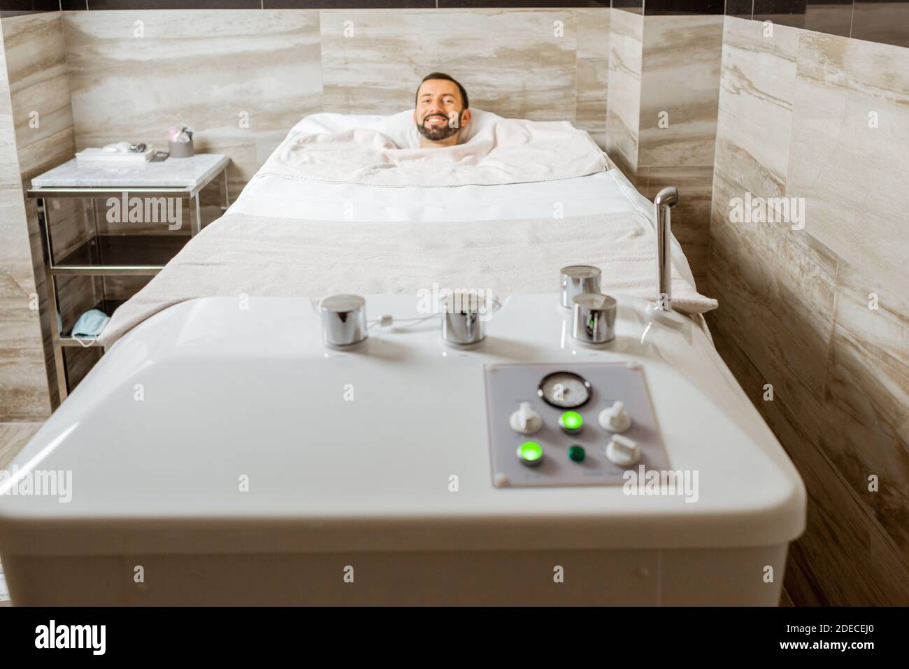Man relaxing during a medical treatment at the bath filled with carbon ...