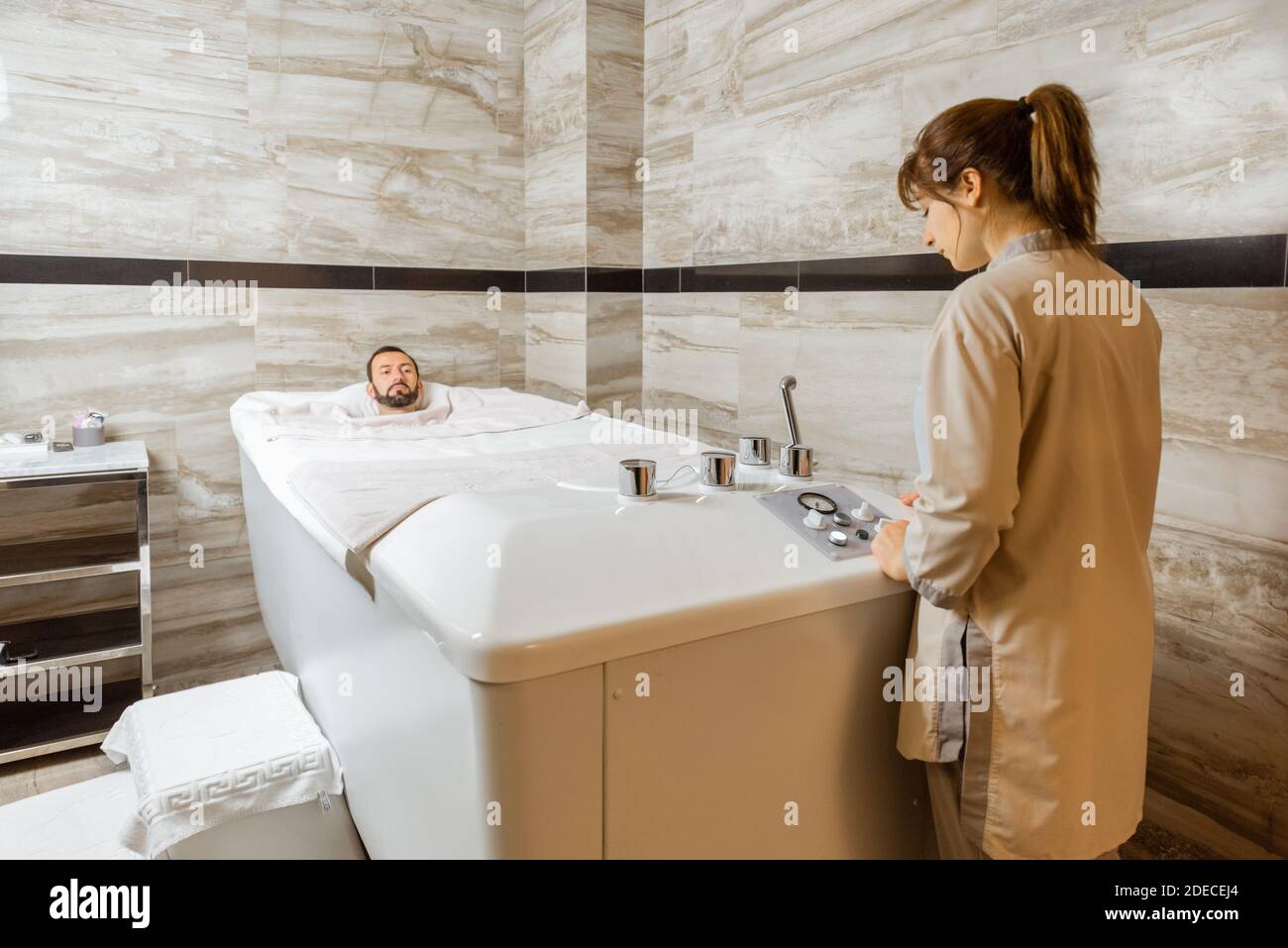 Man relaxing during a medical treatment at the bath filled with carbon ...