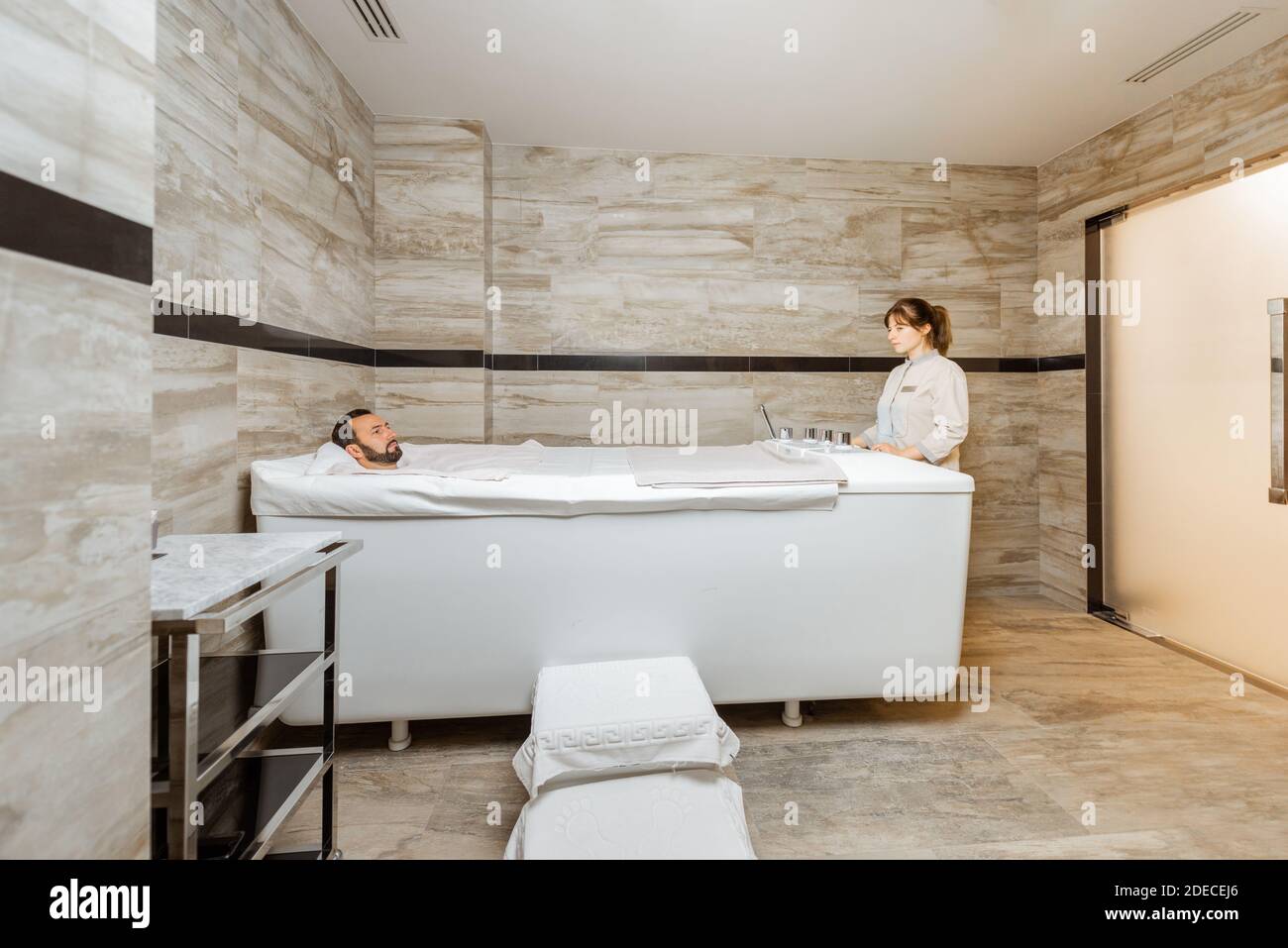 Man relaxing during a medical treatment at the bath filled with carbon ...
