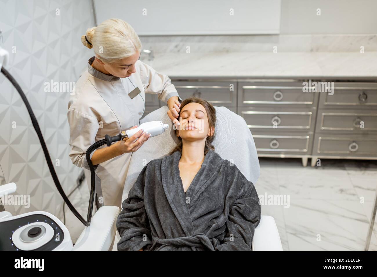 Female doctor making a laser rejuvenation treatment for a young woman ...