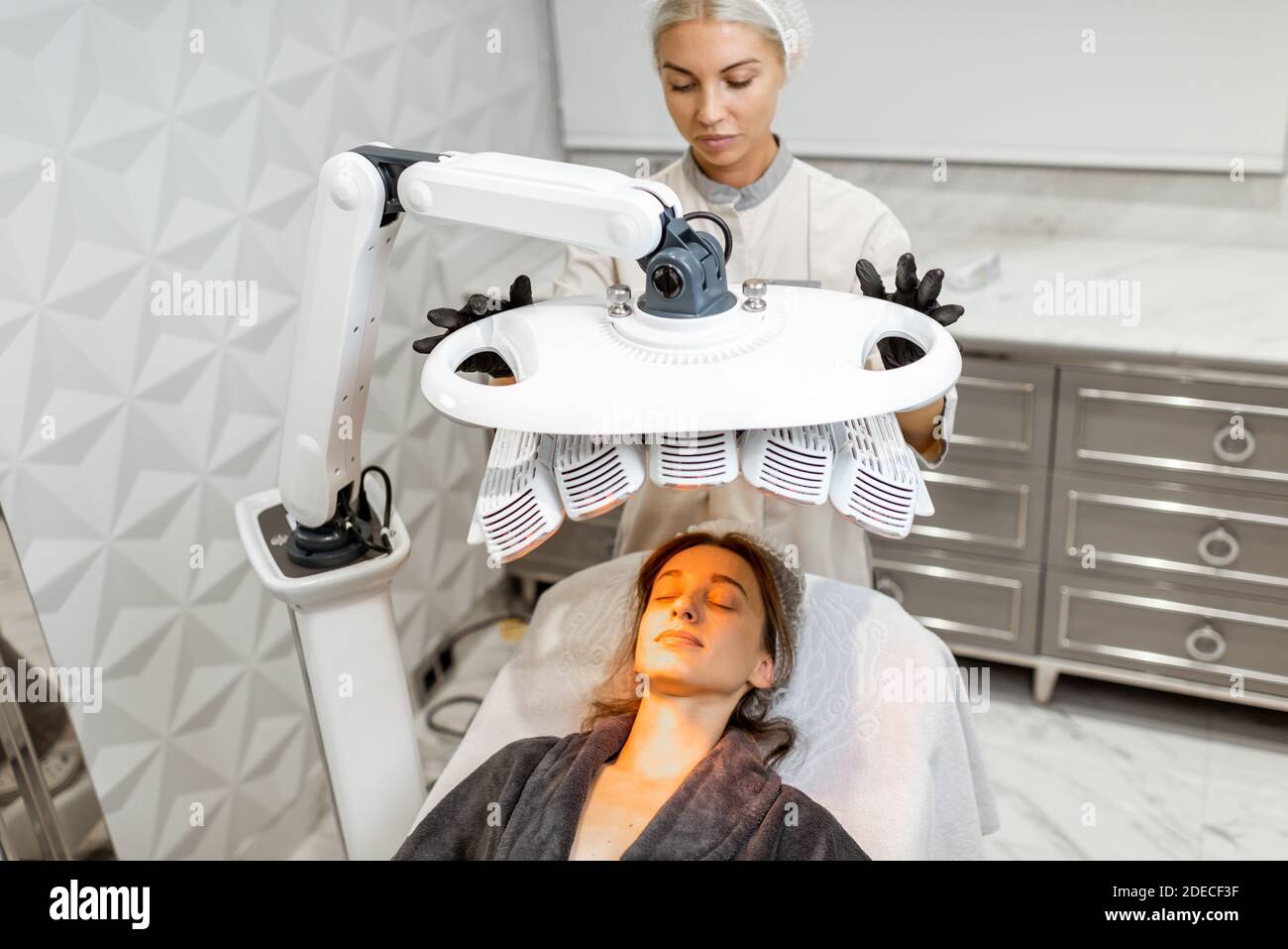 Young woman doing led light therapy on her face with a doctor at luxury ...