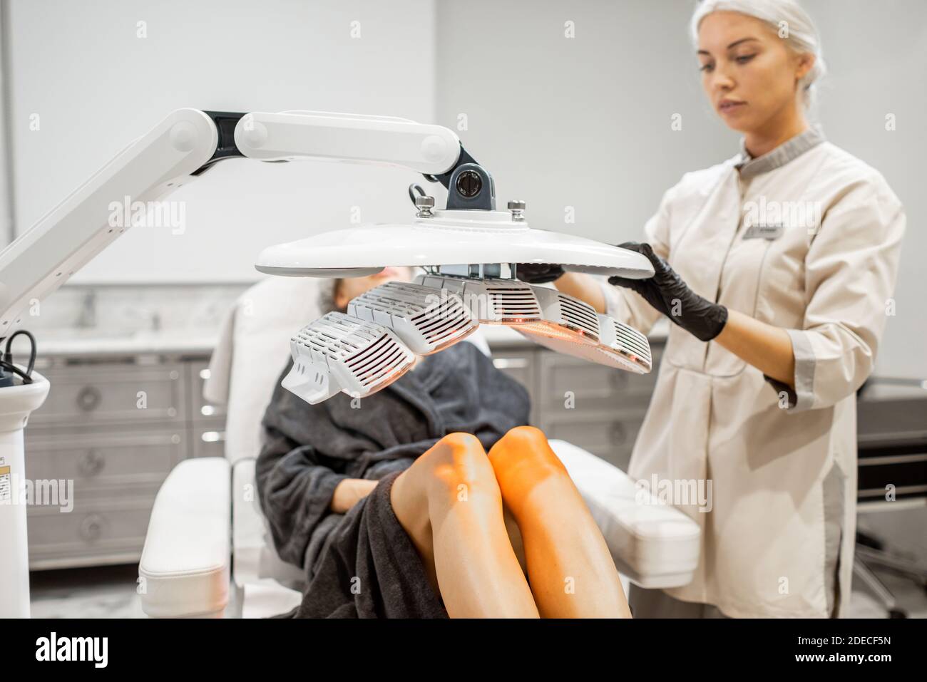 Woman doing led light therapy on her legs with a doctor at luxury ...