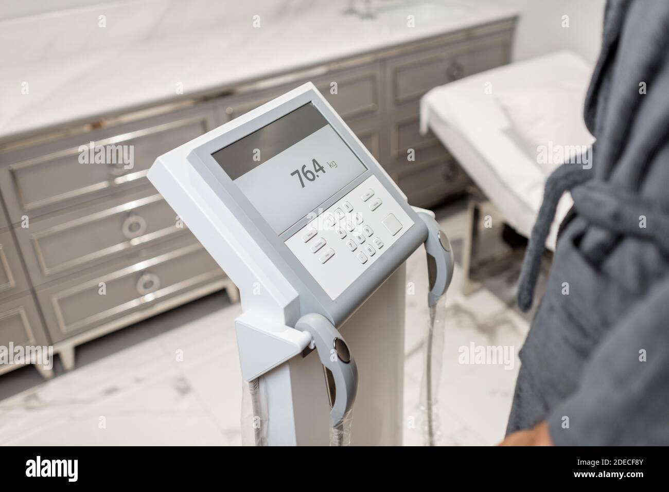 Woman measuring body composition balance, holding handles of a medical ...