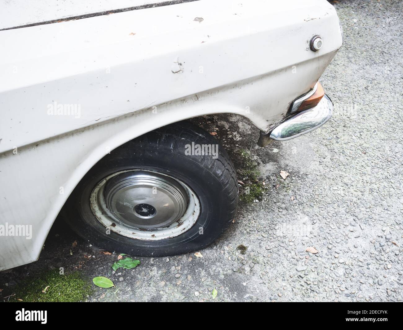A fragment of a white slightly flaky Russian old car with a black wheel ...