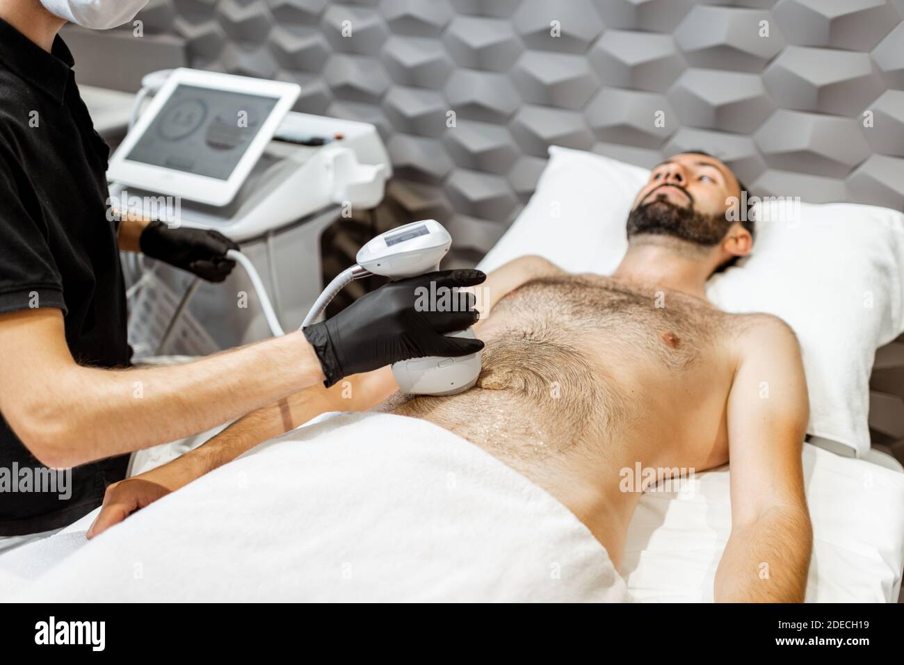 Man during an ultrasound liposuction procedure at luxury Spa salon ...