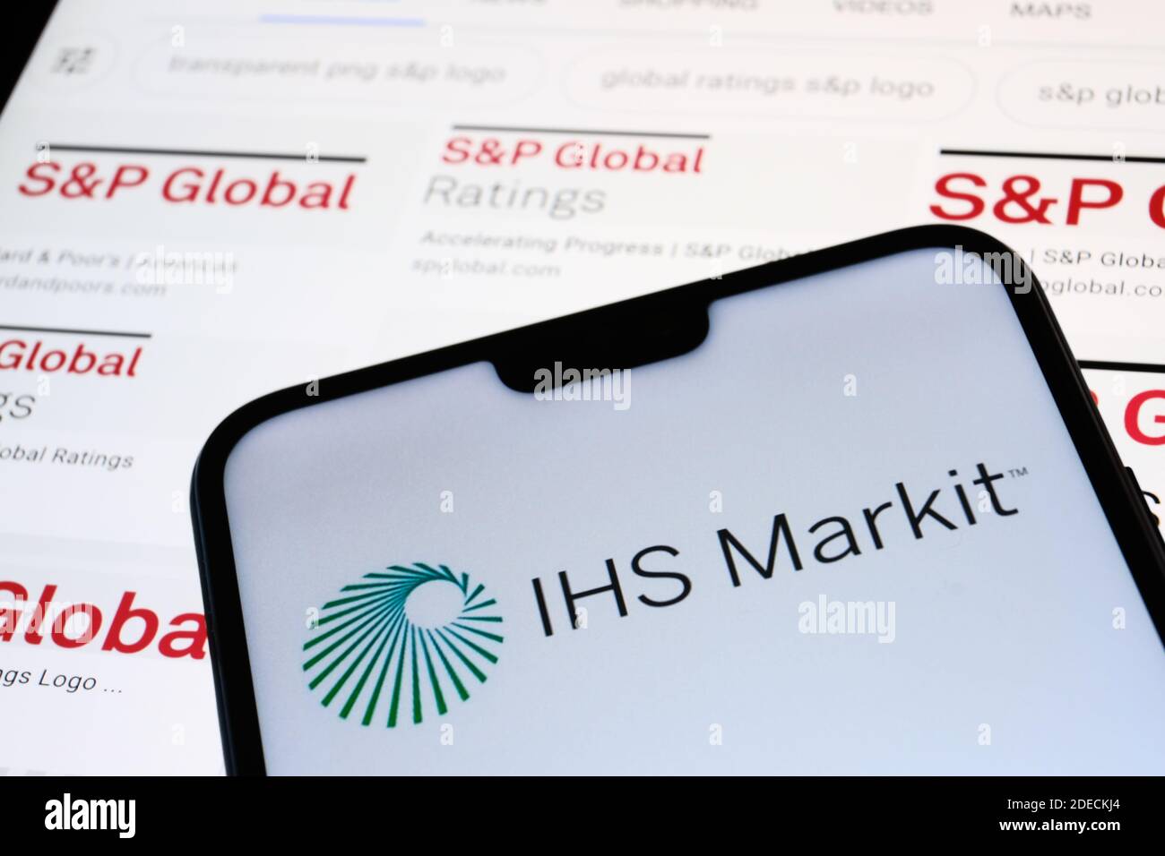 IHS Markit logo seen on the smartphone placed on the screen with the S&P logos. Concept for ...