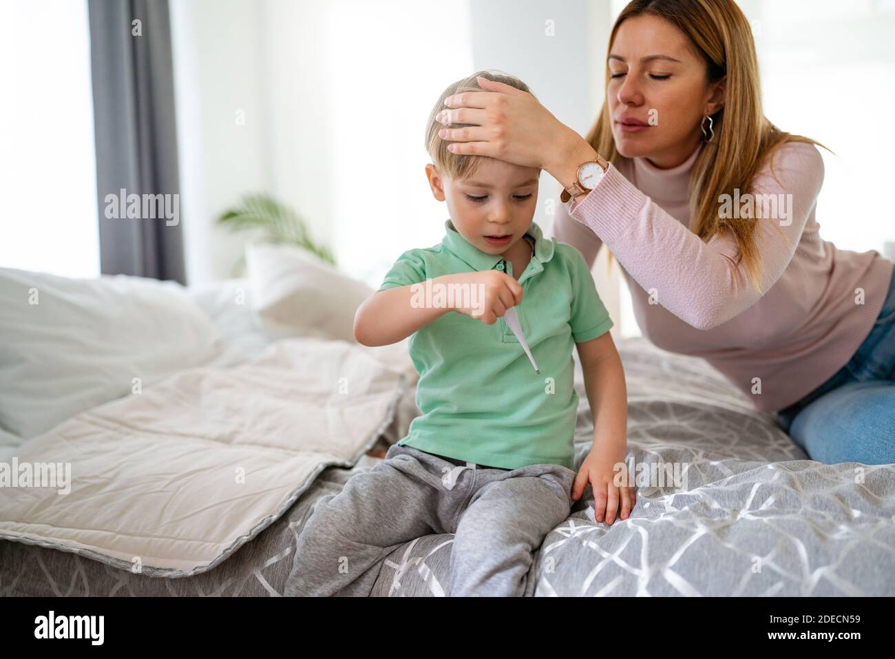 Mother measuring temperature of her ill kid. Sick child with high fever, mother holding ...