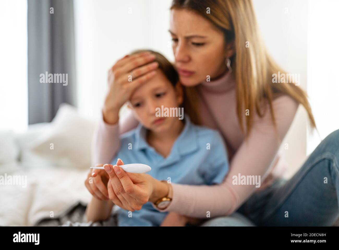 Mother measuring temperature of her ill kid. Sick child with high fever, mother holding ...