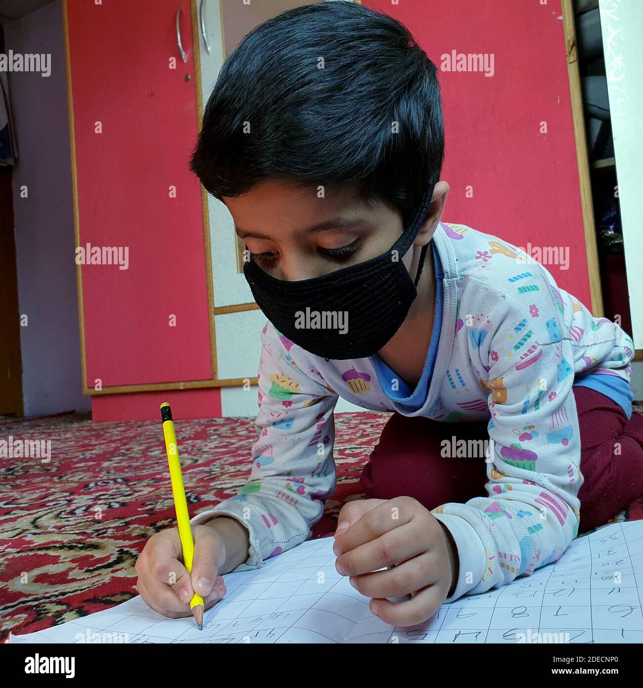 Masked students reading and writing their school work at home during ...