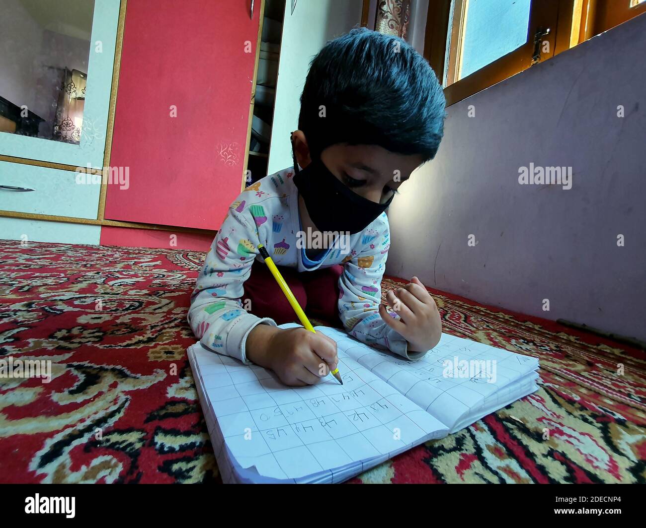 Masked students reading and writing their school work at home during ...