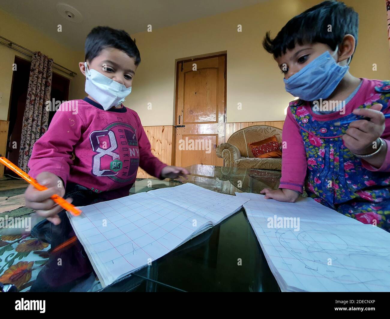 Masked students reading and writing their school work at home during ...