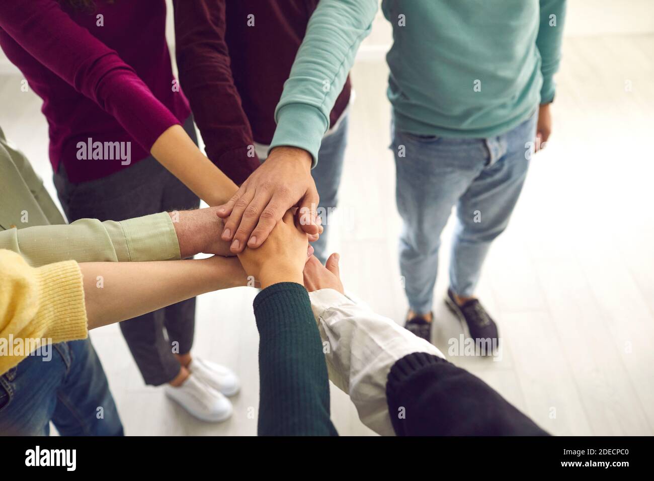 High angle close-up of team of people joining their hands united by a ...