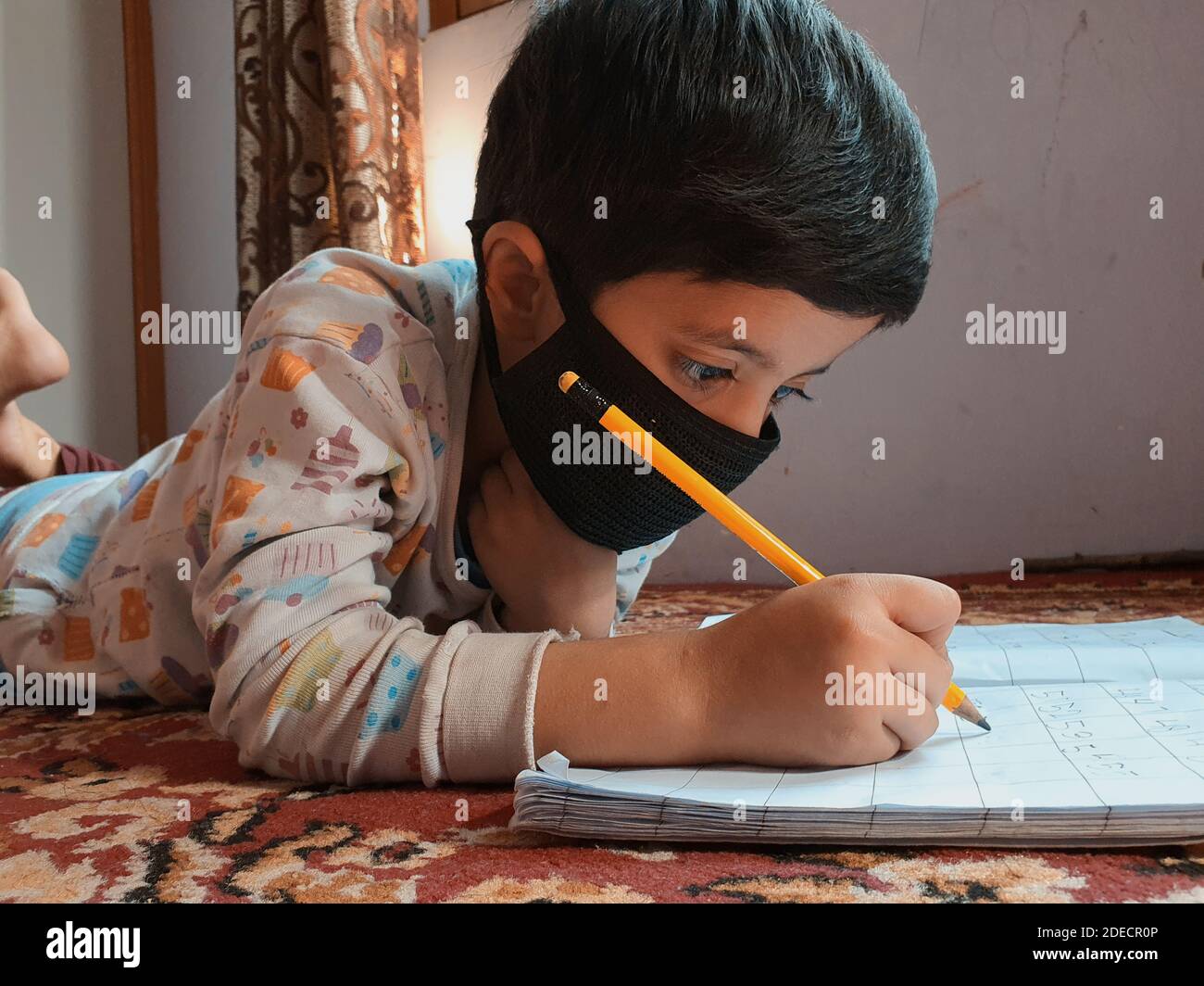 Students wearing masks reading and writing their school work at home ...