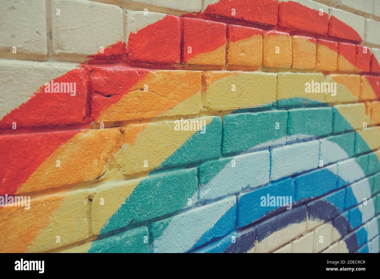 An image of the Rainbow flag painted on a brick wall in an urban ...