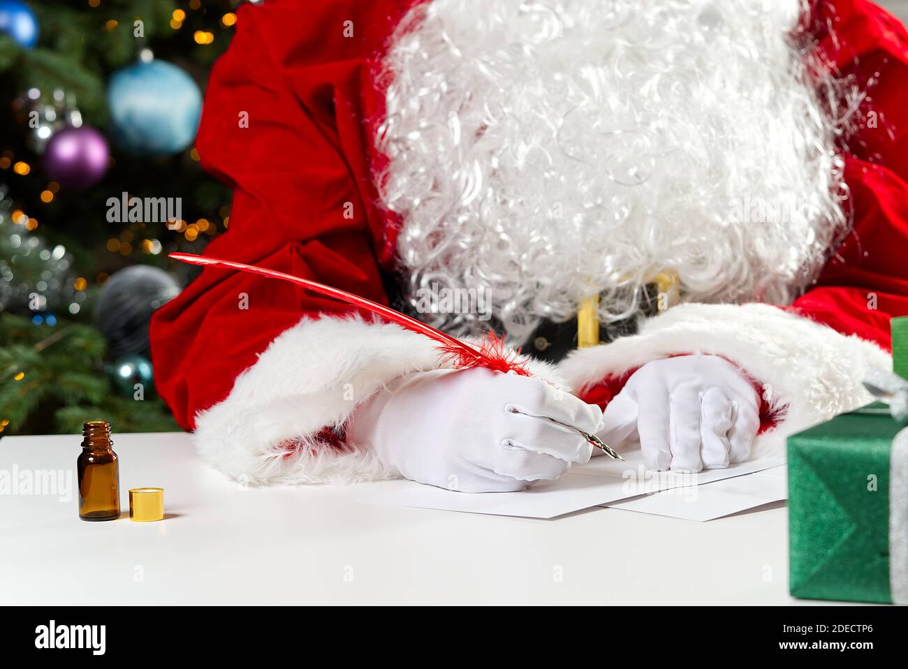 Costumed hands of Santa Claus writing a Christmas letter or greeting on ...