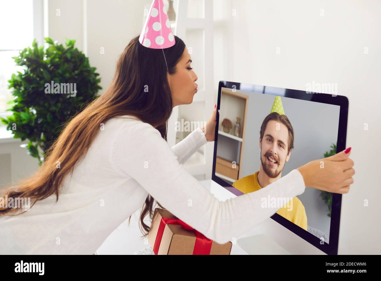 Young woman having online birthday party with her boyfriend and kissing ...