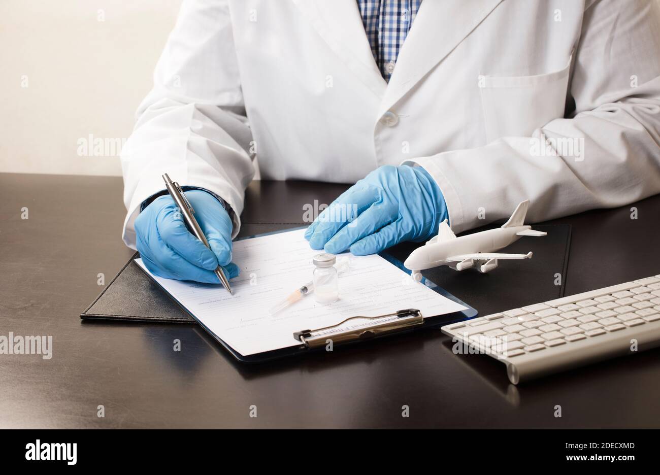 Doctor's hand with pen filling in data, on form, with vaccine, syringe ...