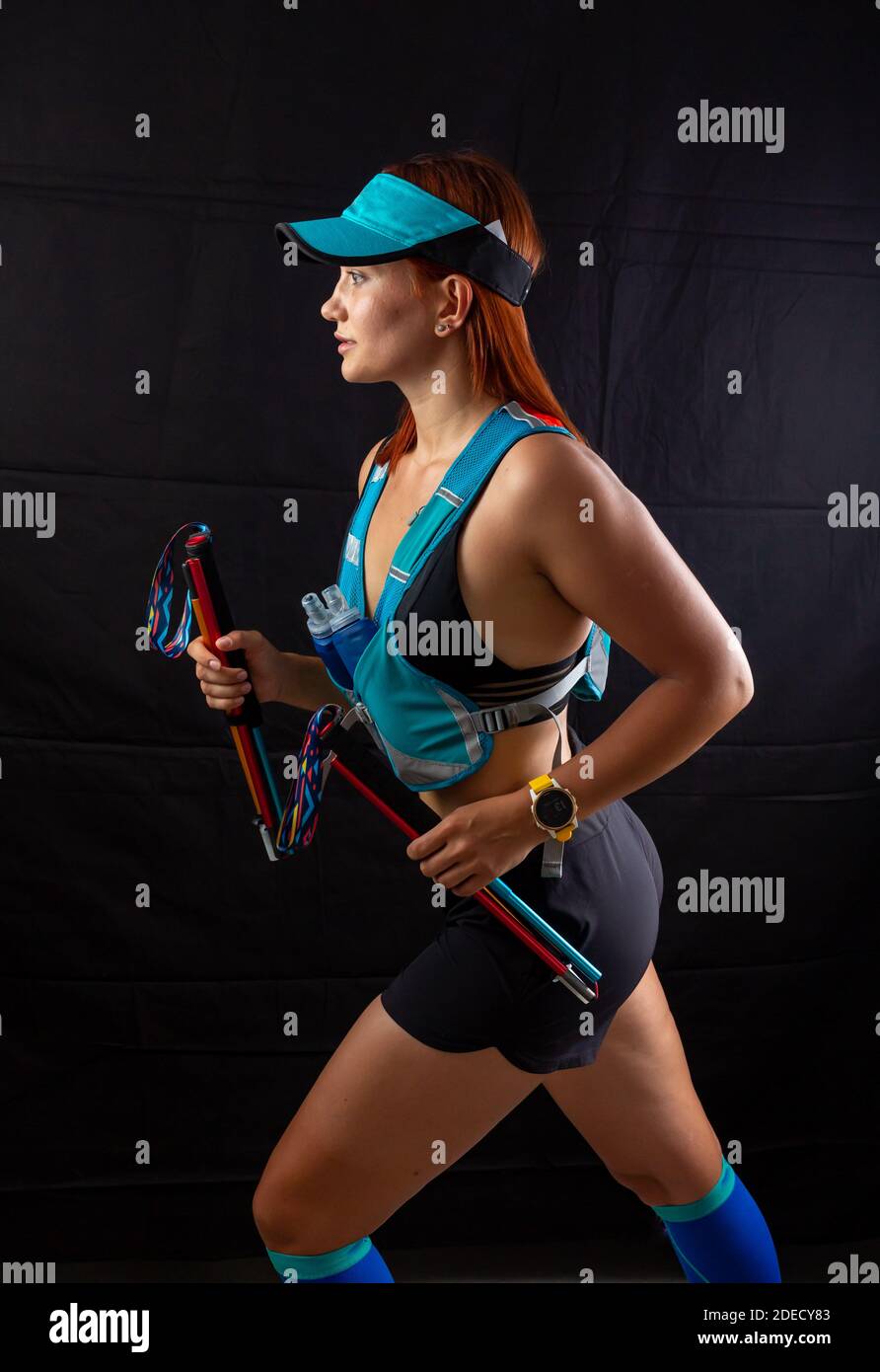Girl marathon runner in full blue uniform runs in the studio on a black ...
