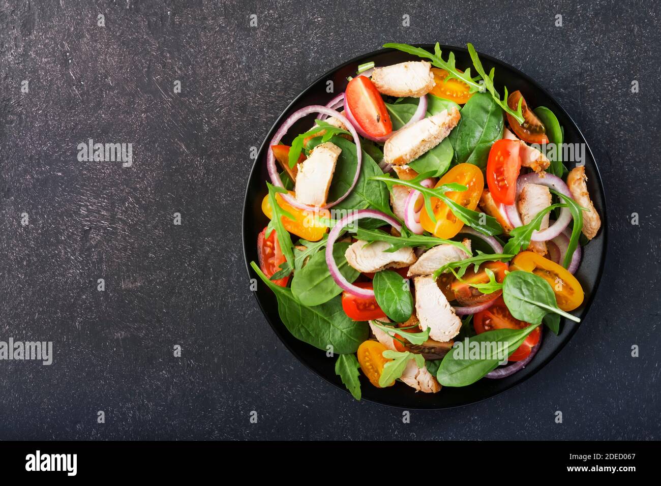 Spring salad with spinach, grilled chicken, cherry tomatoes, arugula, corn salad and red onion ...