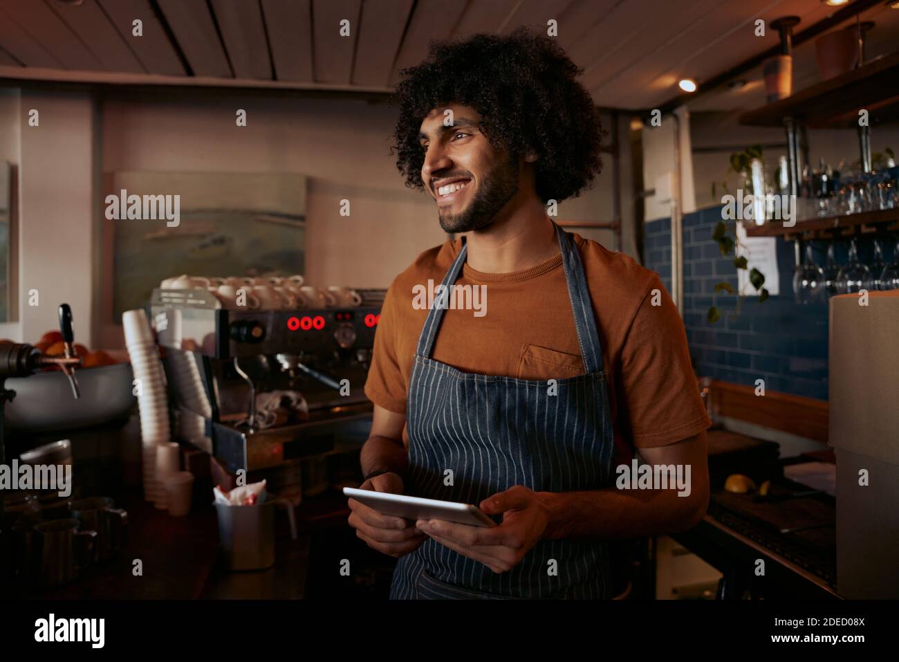 Successful small male business owner wearing apron using digital tablet ...