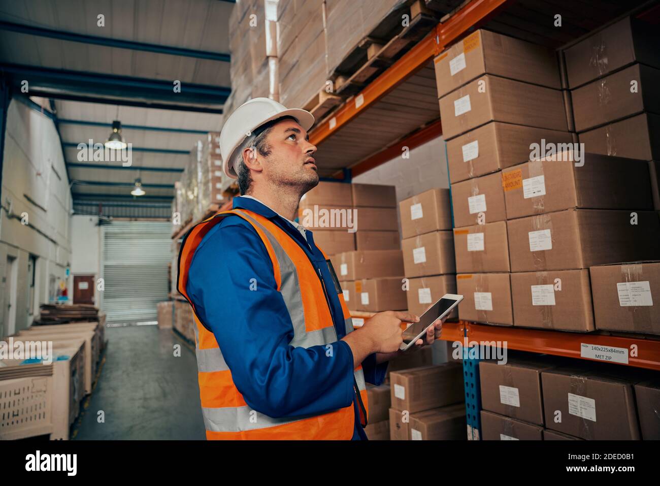 Side view of a male factory worker using digital tablet for maintaining ...