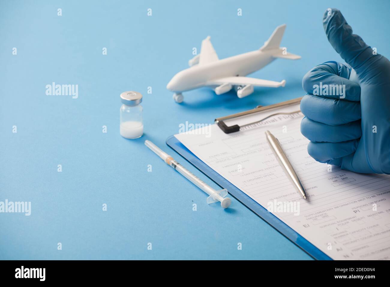 doctor's hand making ok sign, on flight sheet, with vaccine, syringe ...