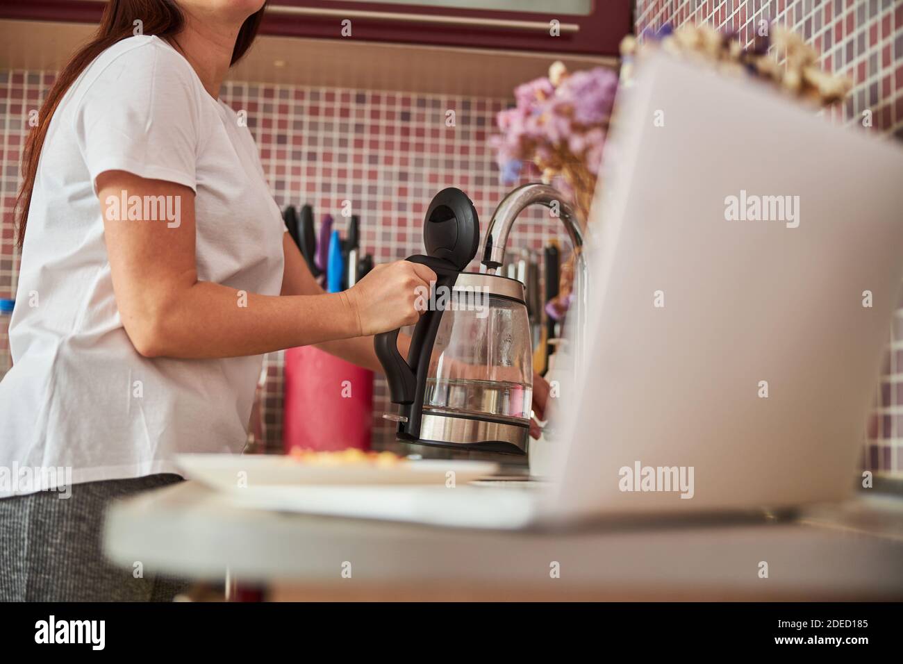 Homemaker is drawing water into the kettle Stock Photo - Alamy