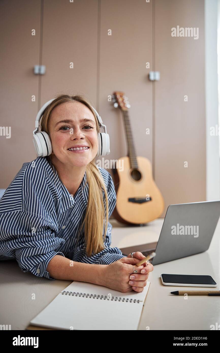 Cheerful female musician in headphones writing songs at home Stock ...