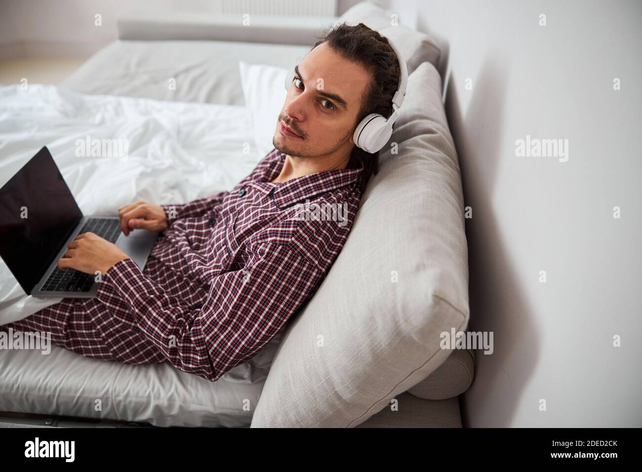Good-looking young man in pajamas using laptop at home Stock Photo - Alamy