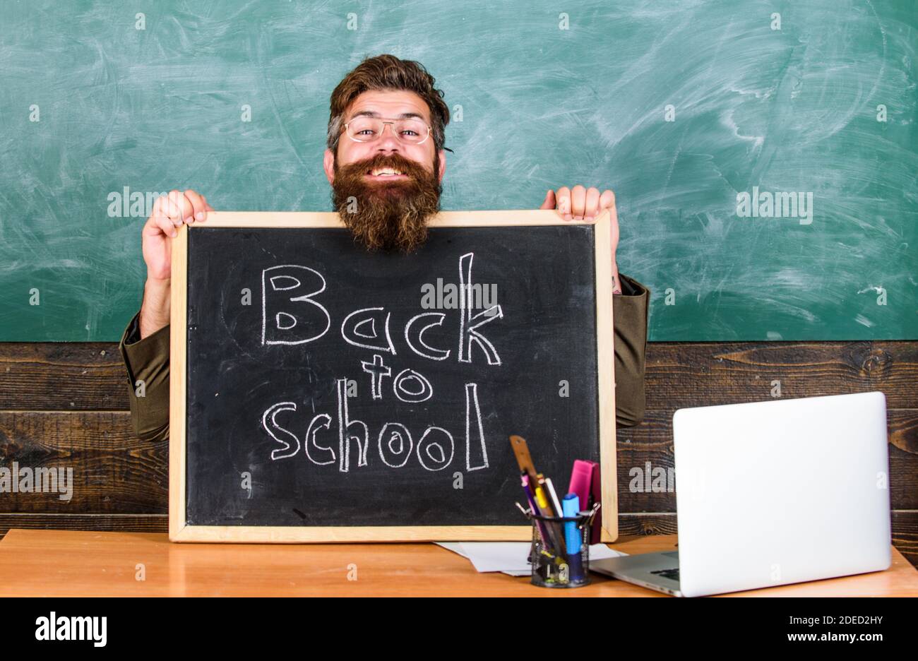 Teacher or school principal welcomes with blackboard inscription back ...