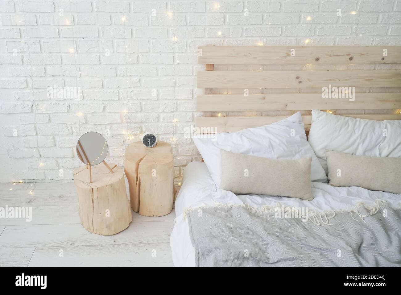Light white interior bed room with wooden objects. Garland on wall ...