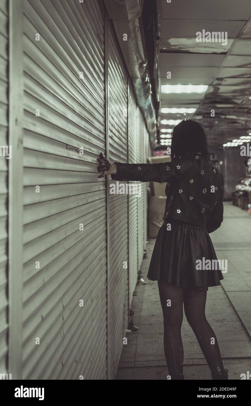 a Halloween scary zombie girl standing with her back and watching ...