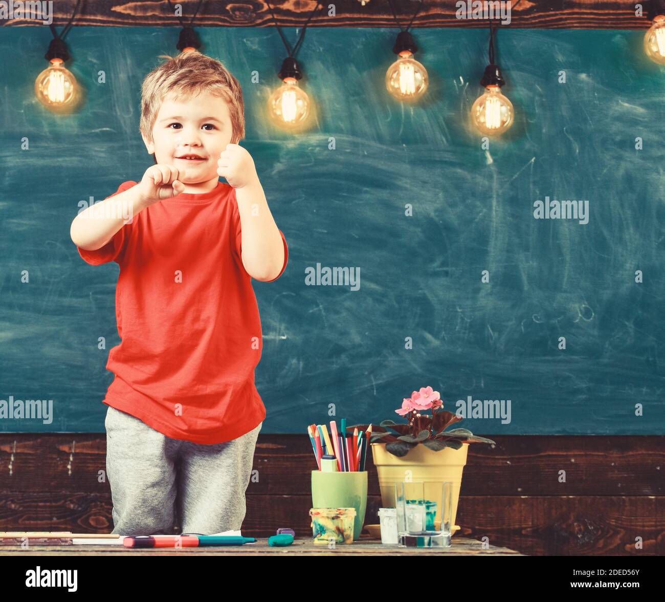 Small boy standing behind the table. Cute kid boxing in the classroom ...