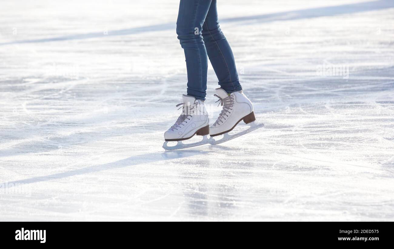 legs of a woman in blue jeans and white skates on an ice rink. hobbies ...