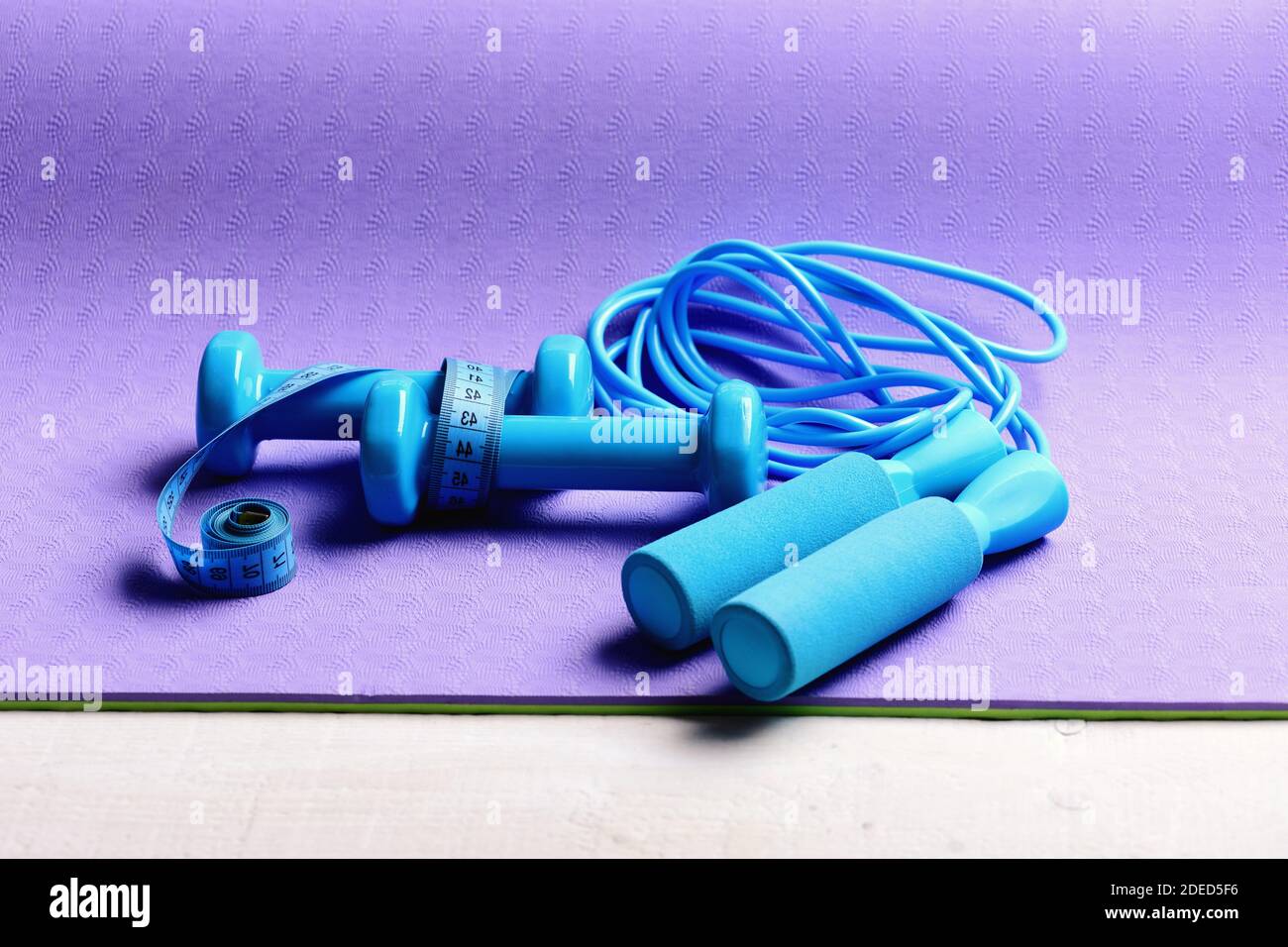 Barbells and skipping rope tied with measure tape roll. Dumbbells and ...