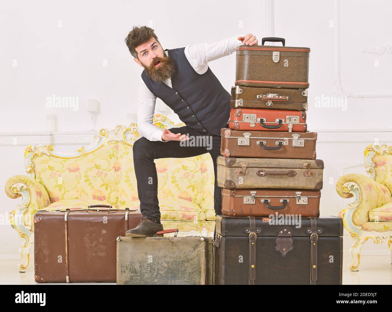Man, butler with beard and mustache delivers luggage, luxury white ...