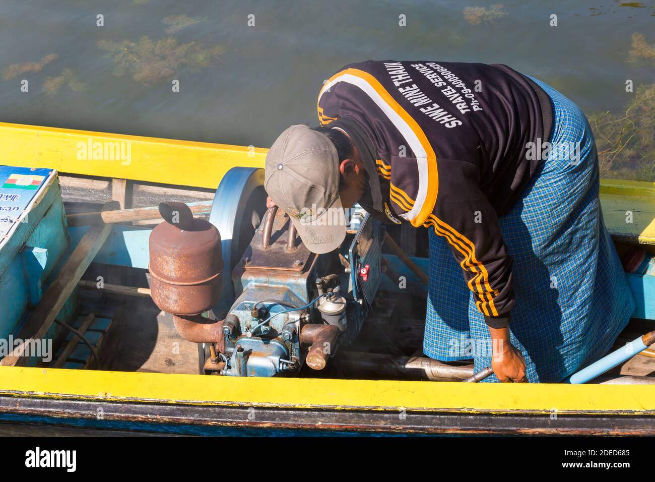 Local man working on engine motor in longboat at Inle Lake, Myanmar ...