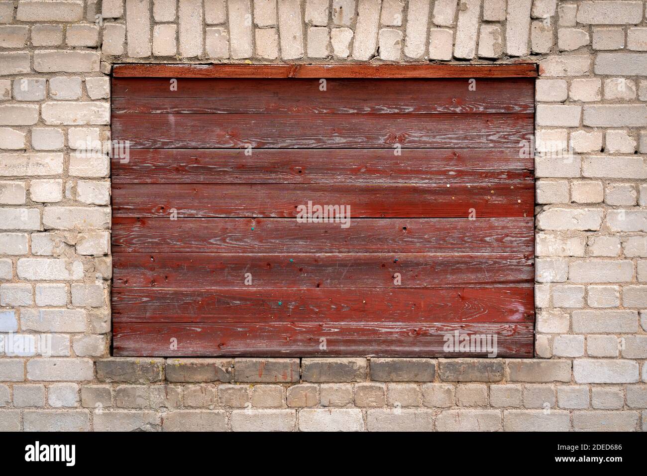 Old wooden noticeboard on the brick wall. Empty rectangular frame for ...